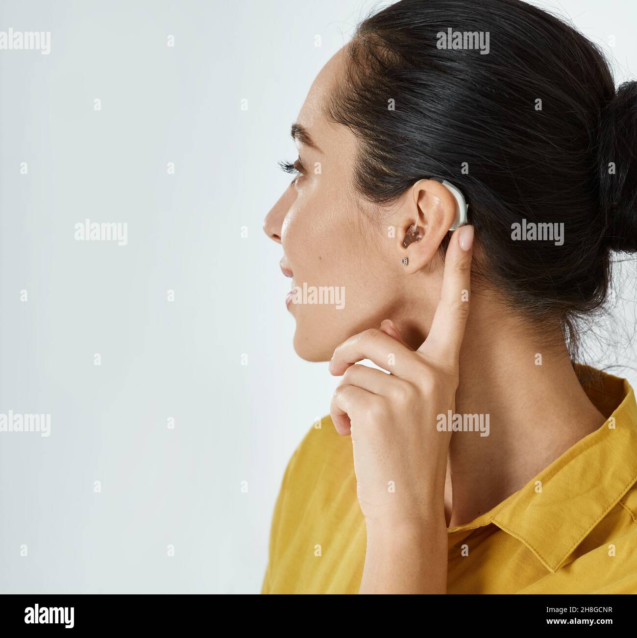 Portrait of woman with hearing aid behind the ear for treatment ...