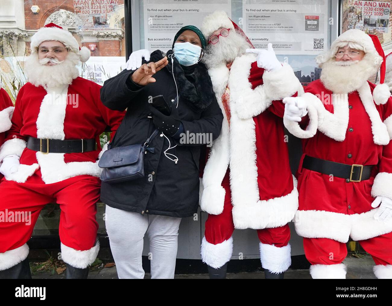Passers-by are greeted by student santas and an elf waiting at a bus ...