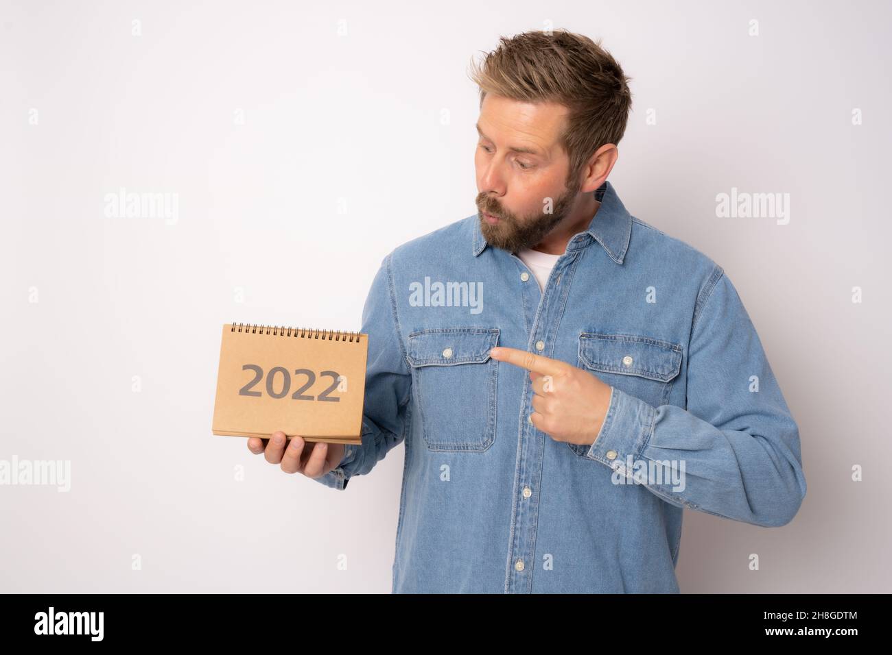 Young excited casual man pointing finger side showing calendar isolated ...