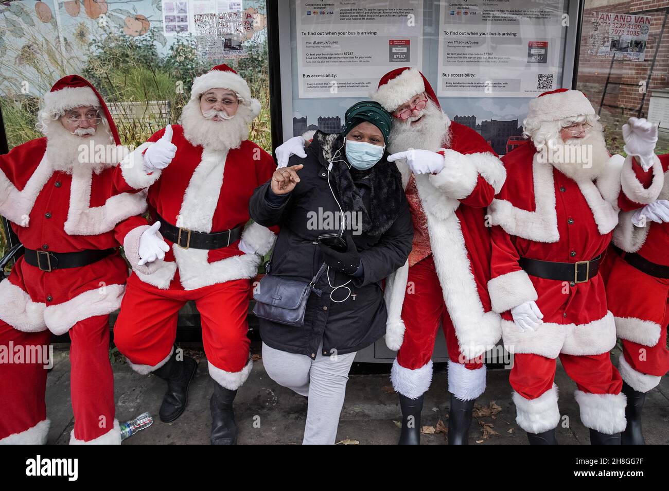London, UK. 30th Nov 2021. Locals meet a Santa performer during Santa ...