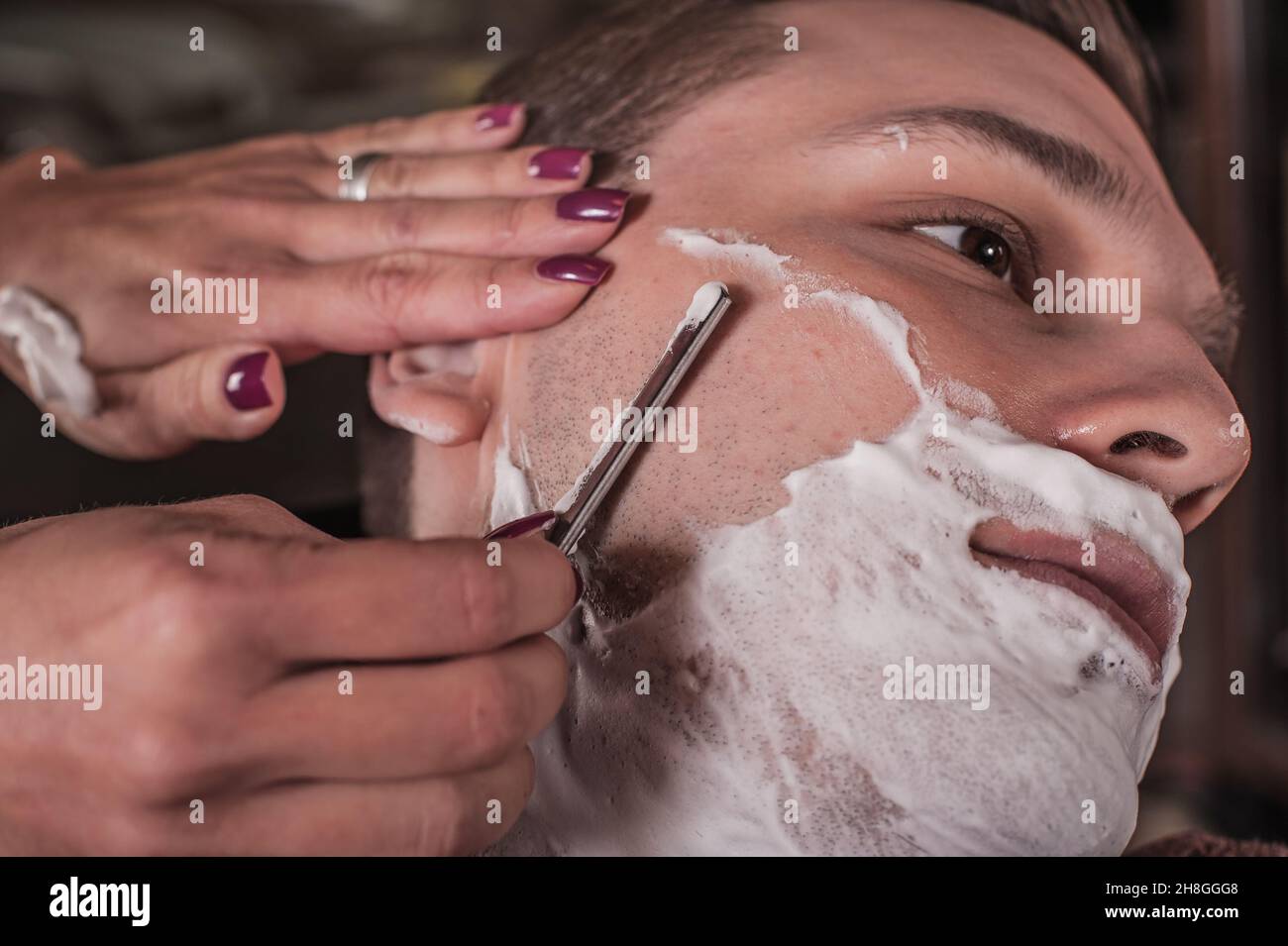Female barber shaving a client's beard in a barber shop. Close-up Stock ...