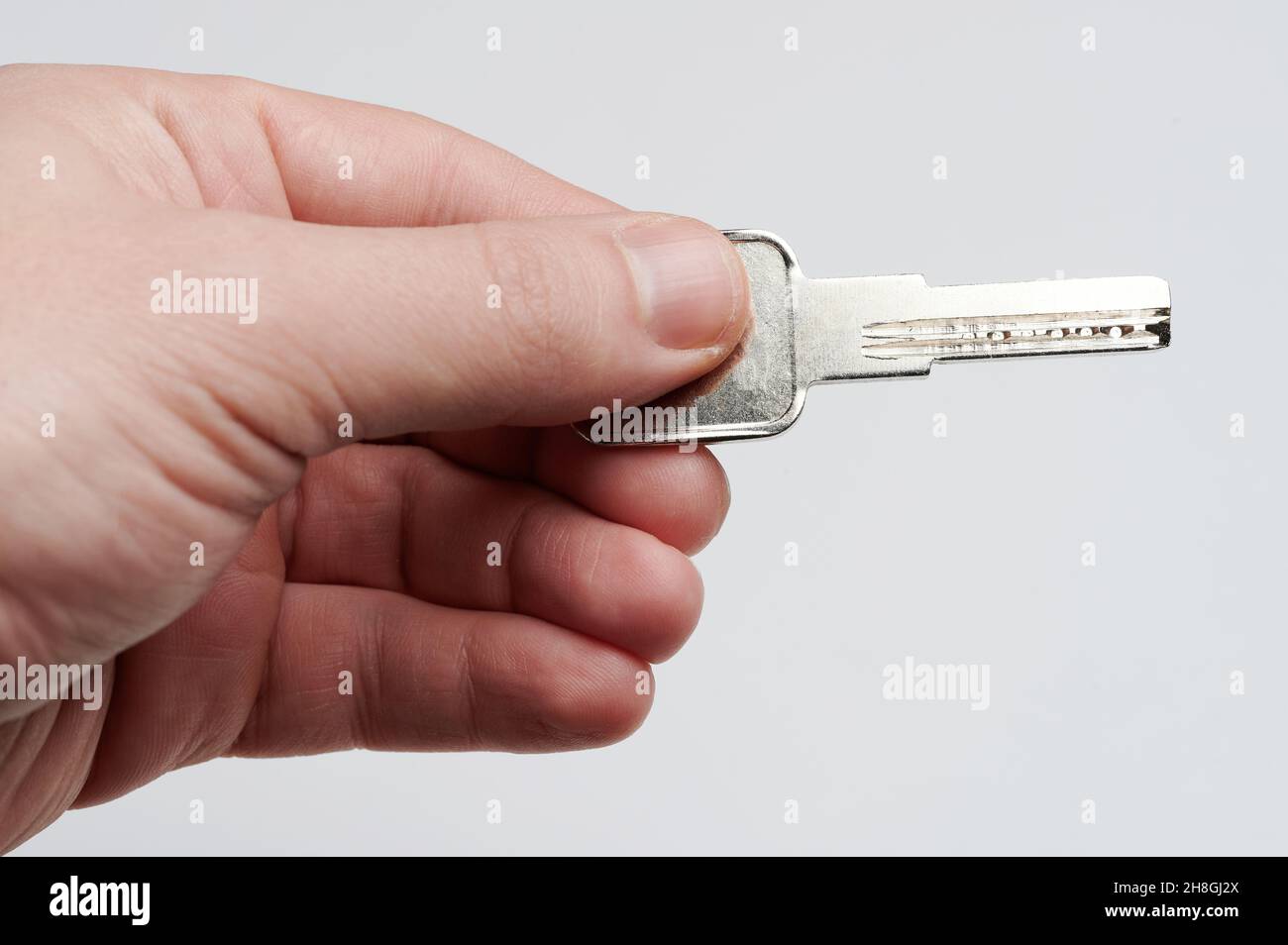 Holding metal flat key hand isolated on studio background Stock Photo ...
