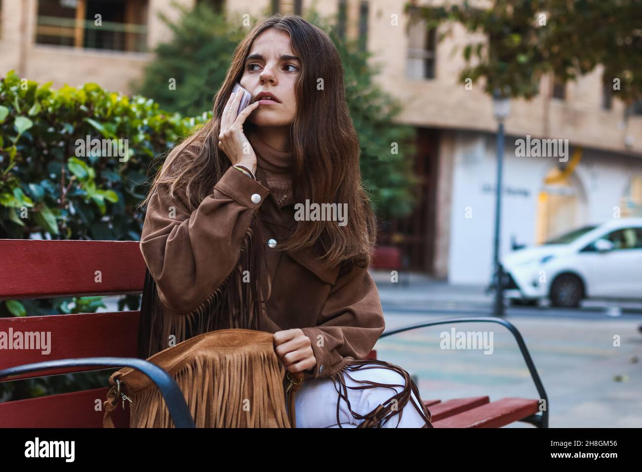 Girl sat in a bench and calling with her phone Stock Photo - Alamy