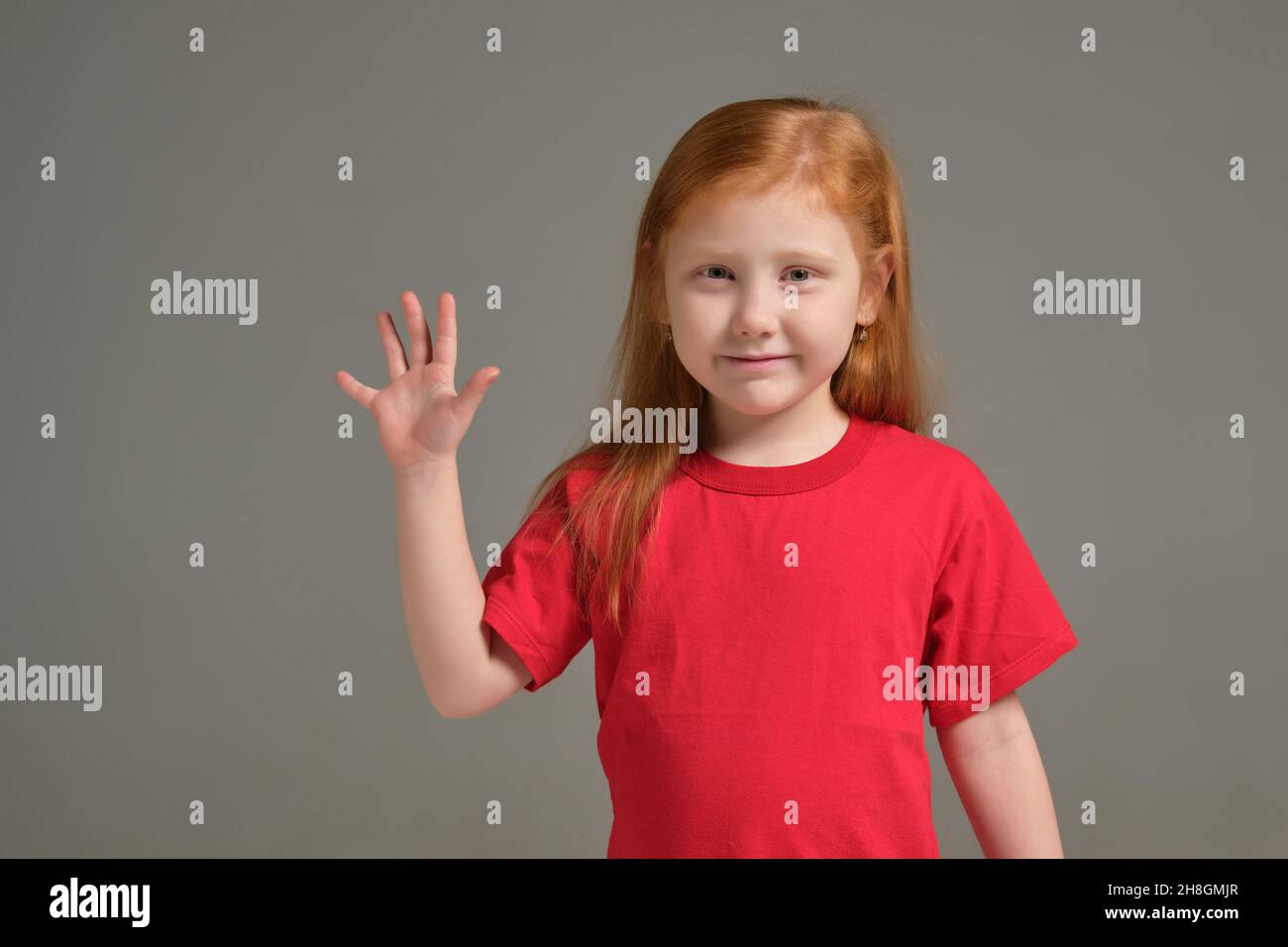 A little girl shows gesture - five fingers, isolated on grey background ...