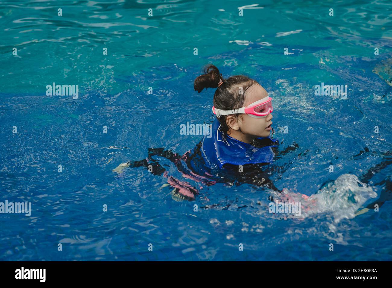 children girl in swimming pool. Wearing goggles and life jackets Stock ...