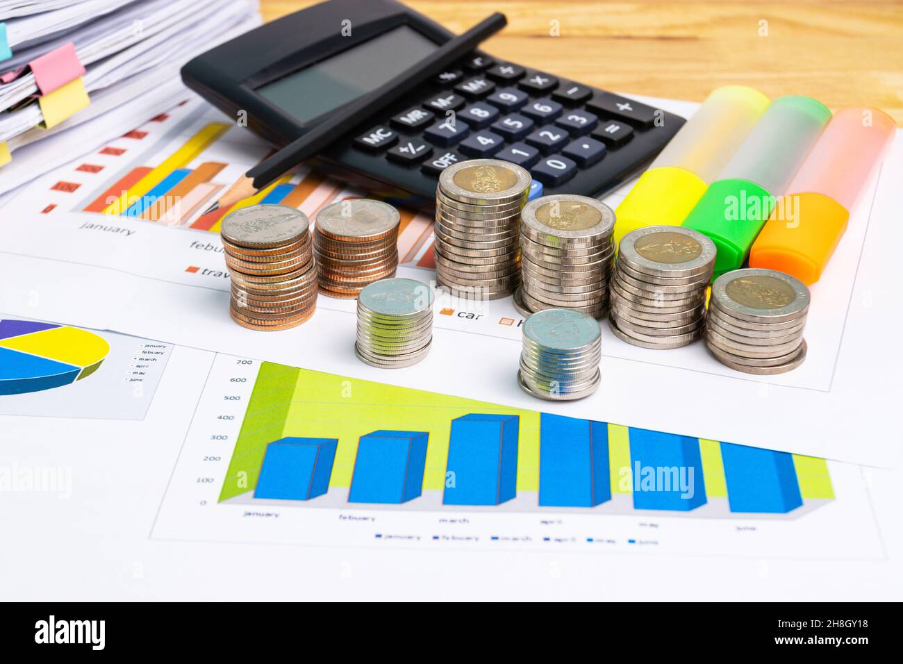 the stack of coin with business paper graphs and pencil with charts ...