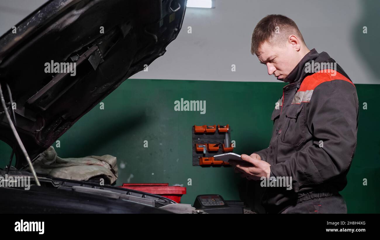 Worker uses digital device to check automobile at station Stock Photo ...