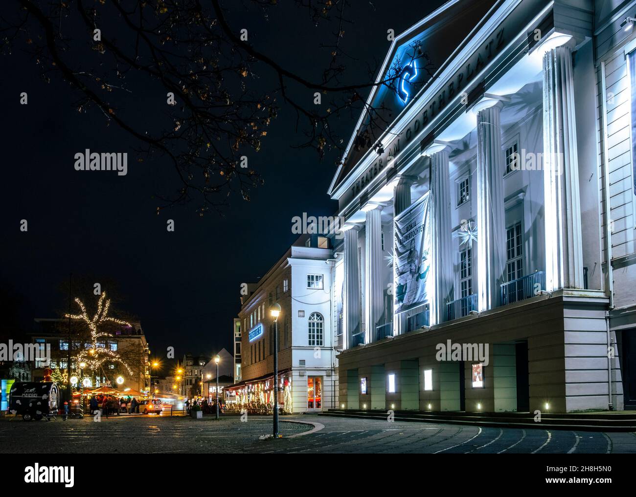 People stand at the brightly lit christmas market in front of the ...
