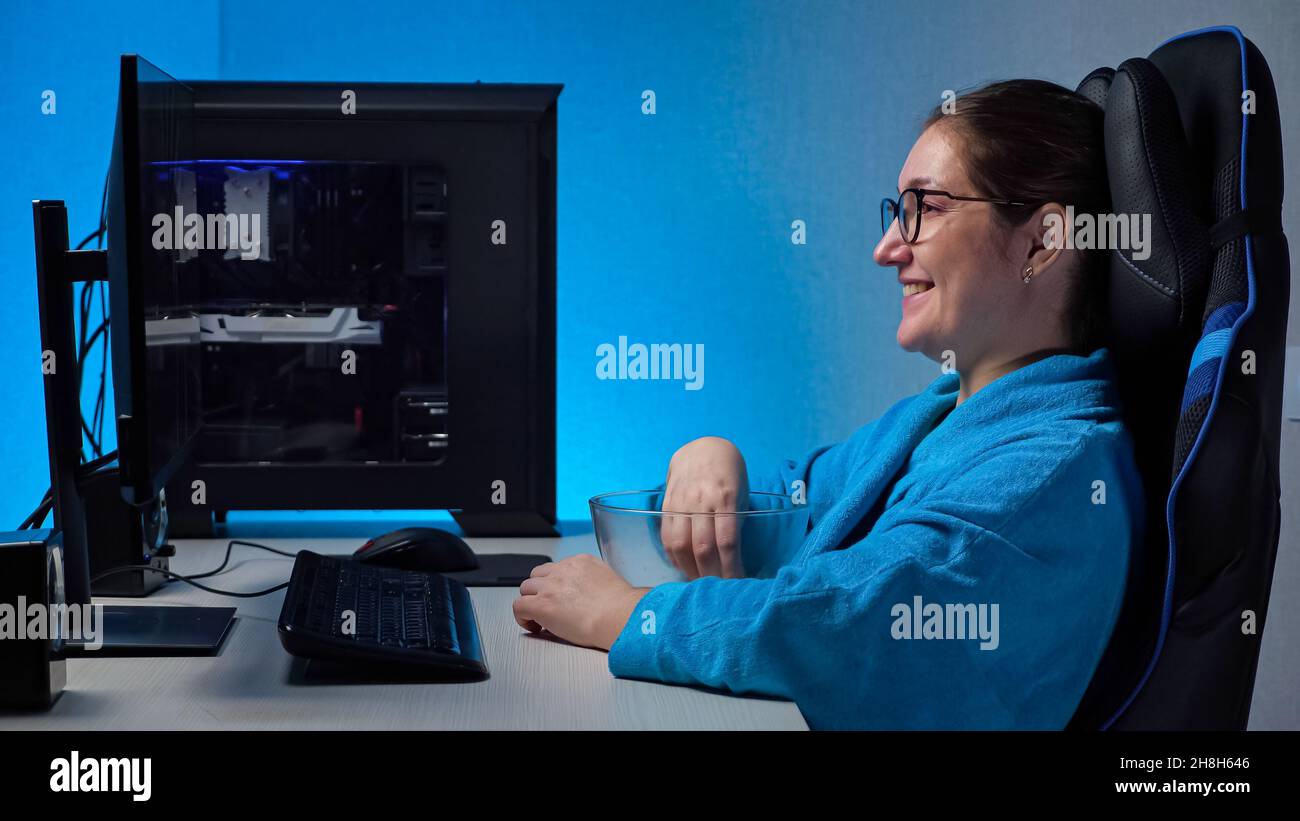 Young woman watches stream with computer and eats popcorn Stock Photo ...