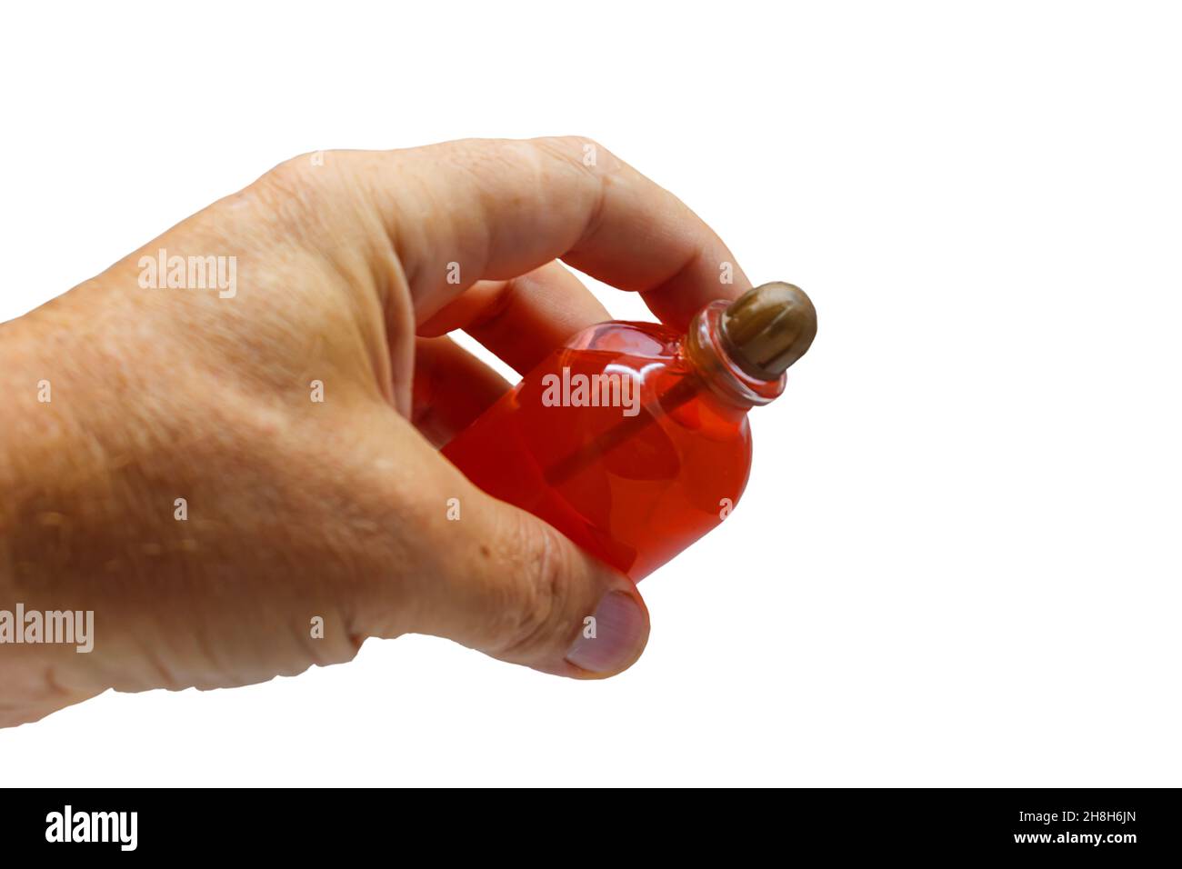 Hand with a glass bottle of oriental fragrant oil close-up. Isolated ...