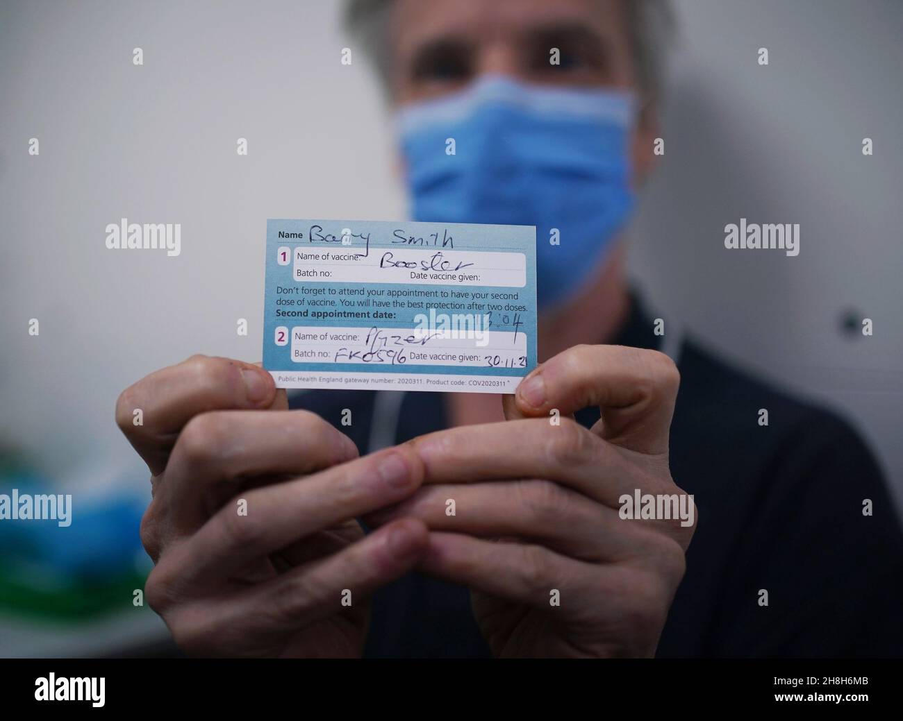 Barry Smith, aged 60, holds his vaccination record card after receiving ...