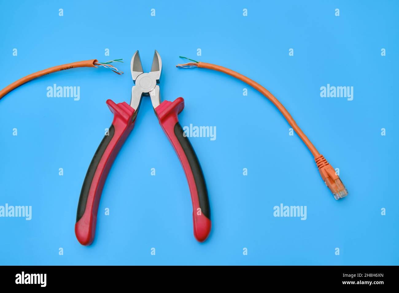 Cutting a computer network wire with wire cutters, blue studio ...