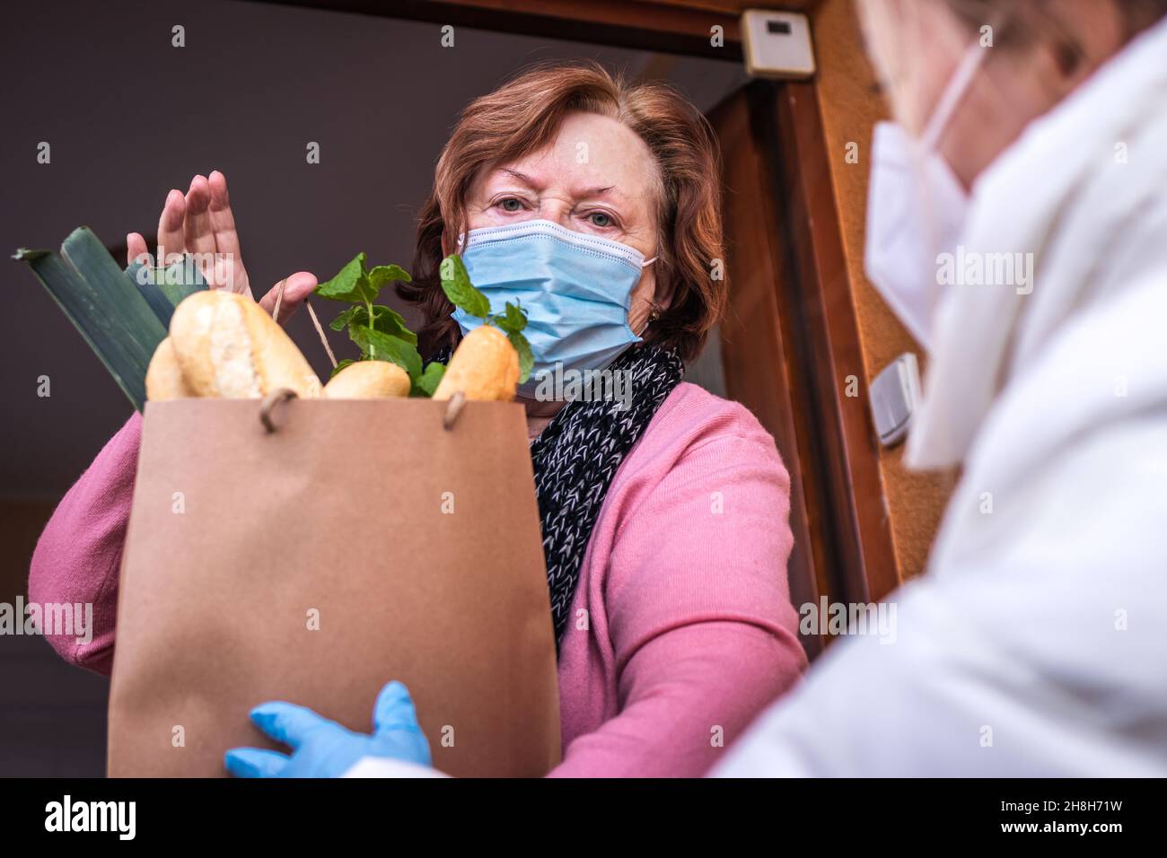 Volunteer wearing ffp2 mask during delivering groceries to senior woman ...