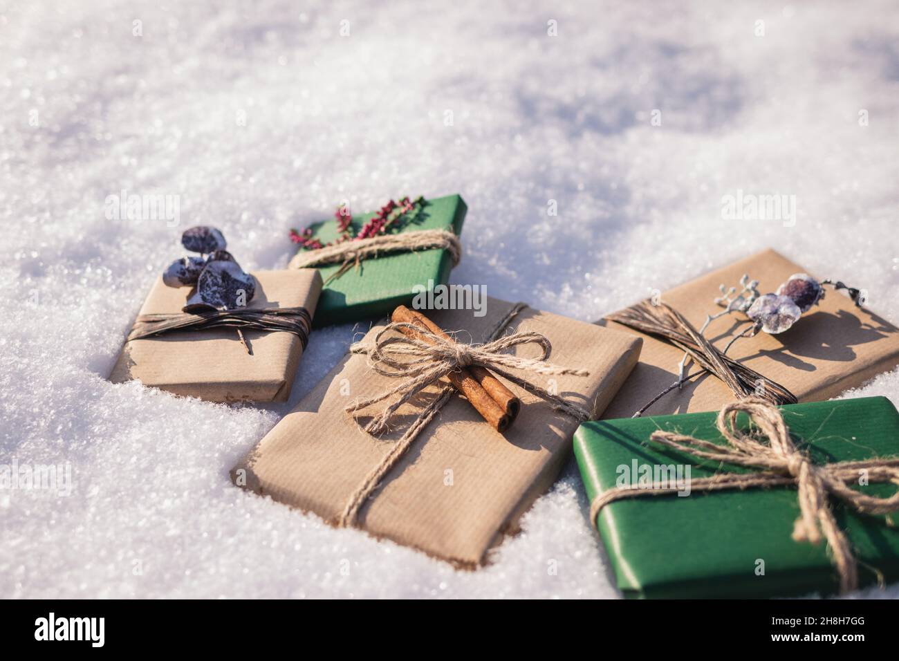 Wrapped Christmas presents with decoration in snow. Gift boxes in green ...