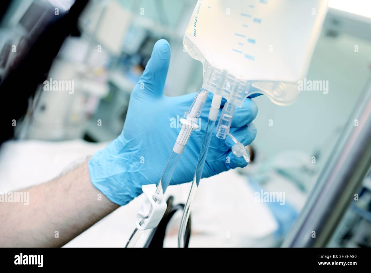 Male medical worker regulate the intravenous drip system at the patient ...