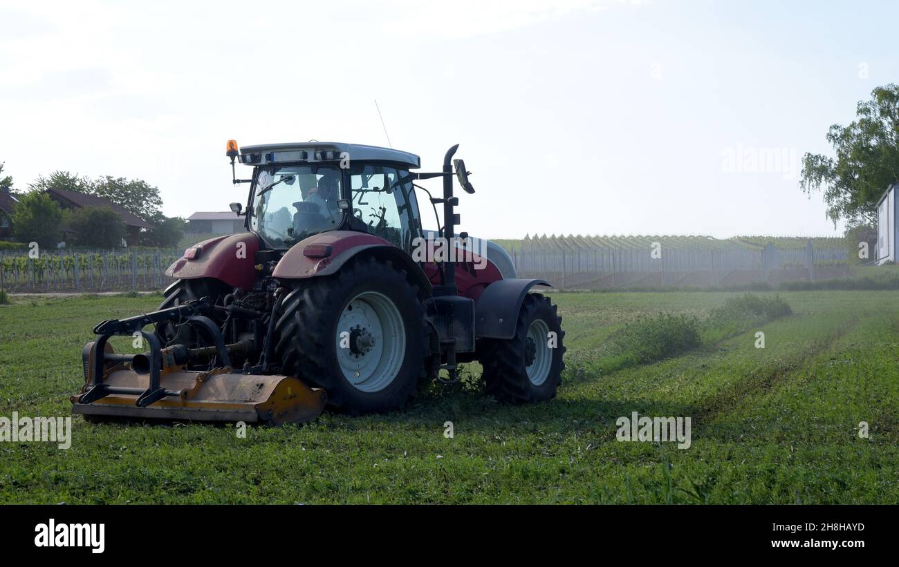 Tractor cultivating a field with a trail of dust Stock Photo - Alamy
