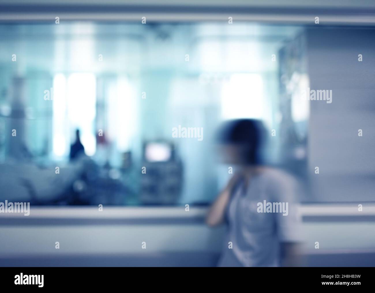Female nurse looking through the observation window of hospital ward ...
