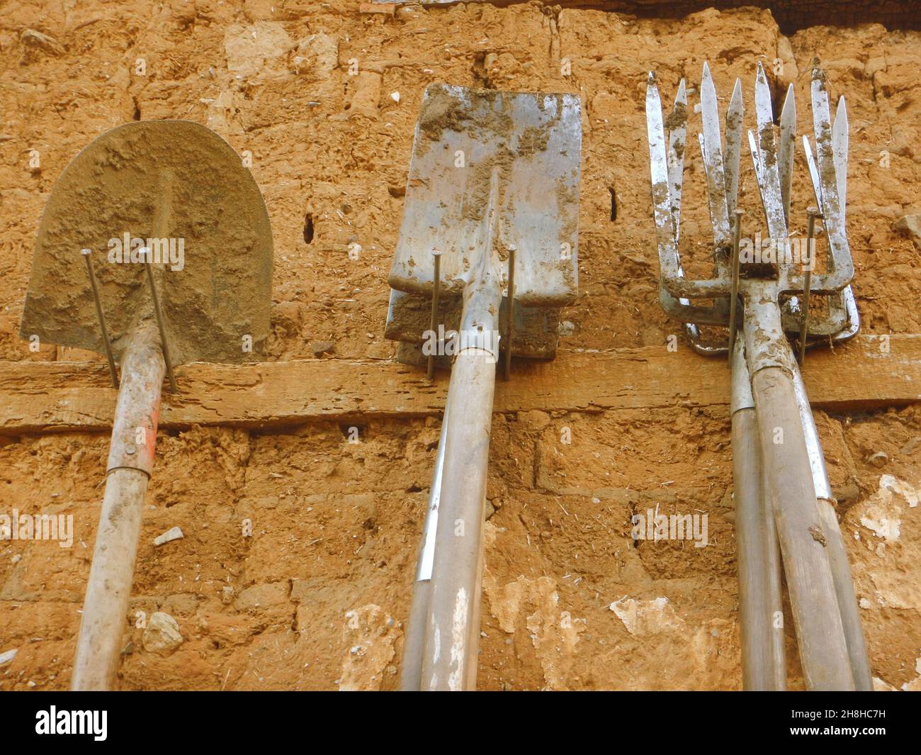 Gardener's tool full of earth hung on mud house wall Stock Photo - Alamy