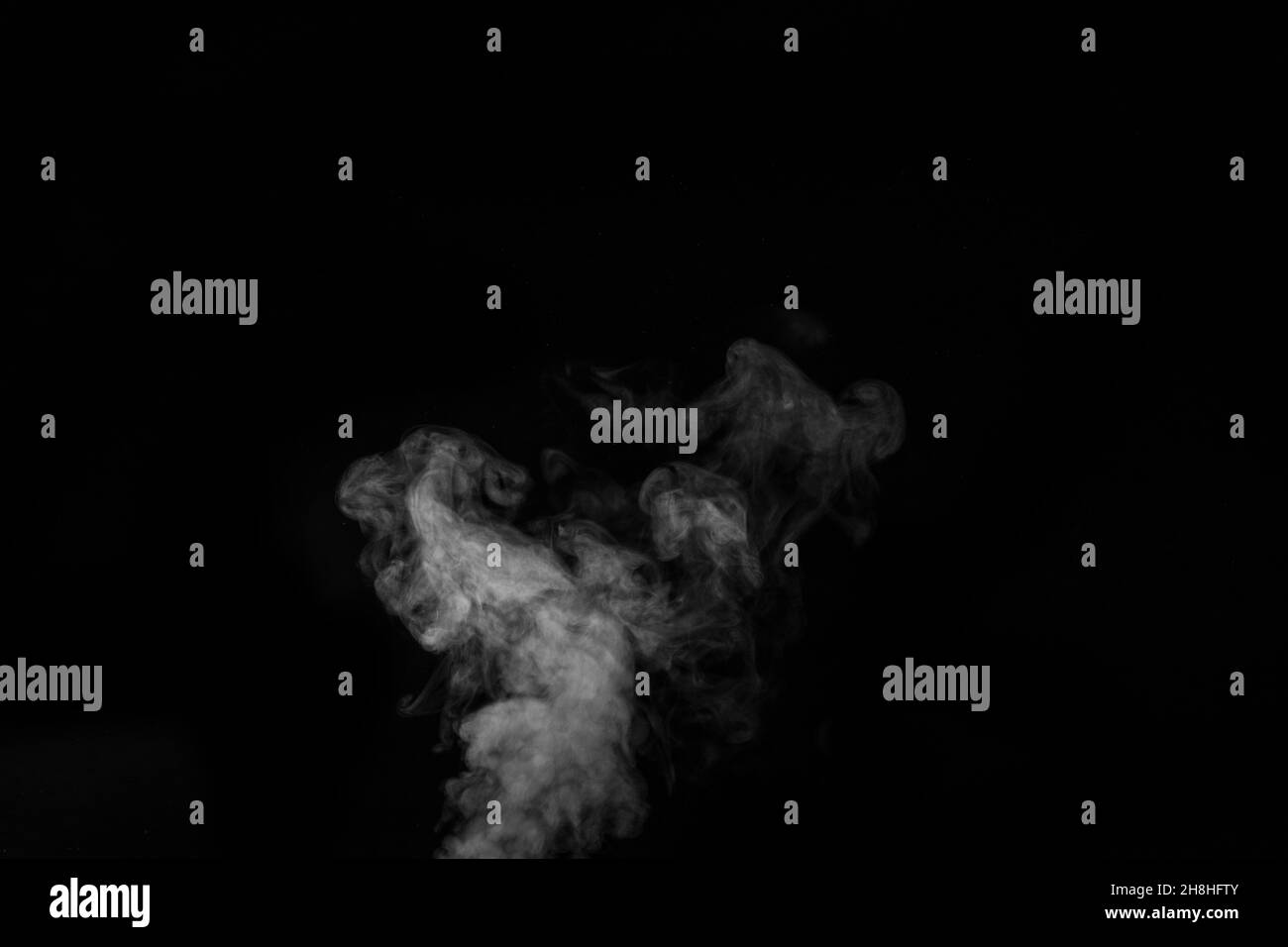 White vapor spray steam from air saturator. Smoke fragments on a black ...