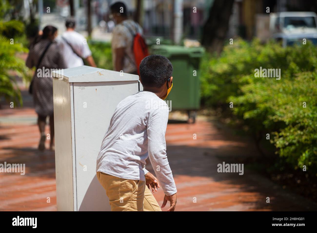 A cheeky young Indian boy hide behind a cover to play with his family ...