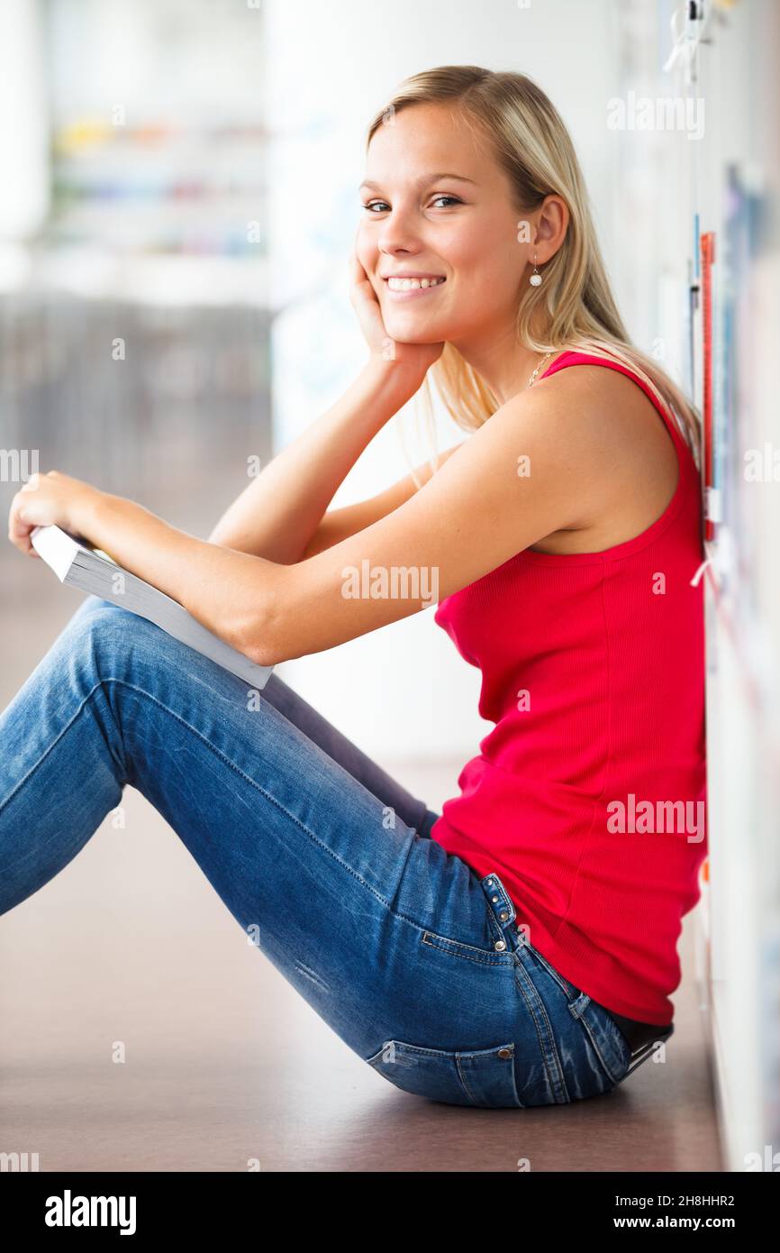 in the library - pretty female student with books working in a high ...