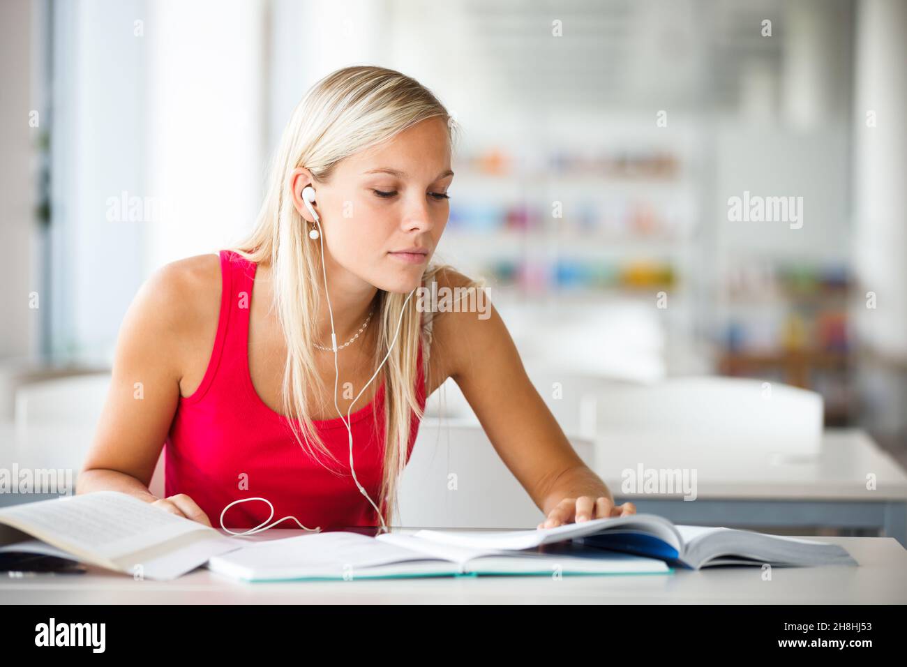 In the library - pretty female student with books working in a high ...
