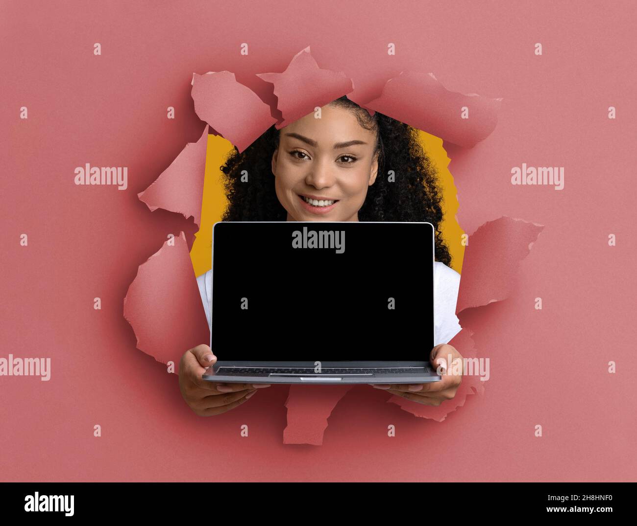 Black young lady showing empty laptop screen through slit paper Stock ...