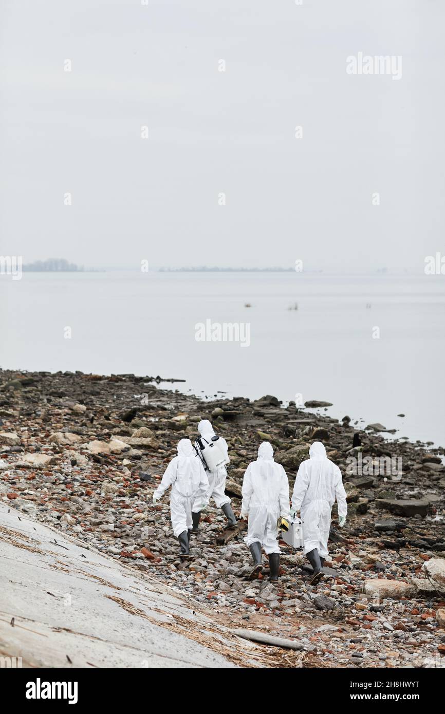 Vertical wide angle view at group of workers wearing hazmat suits ...