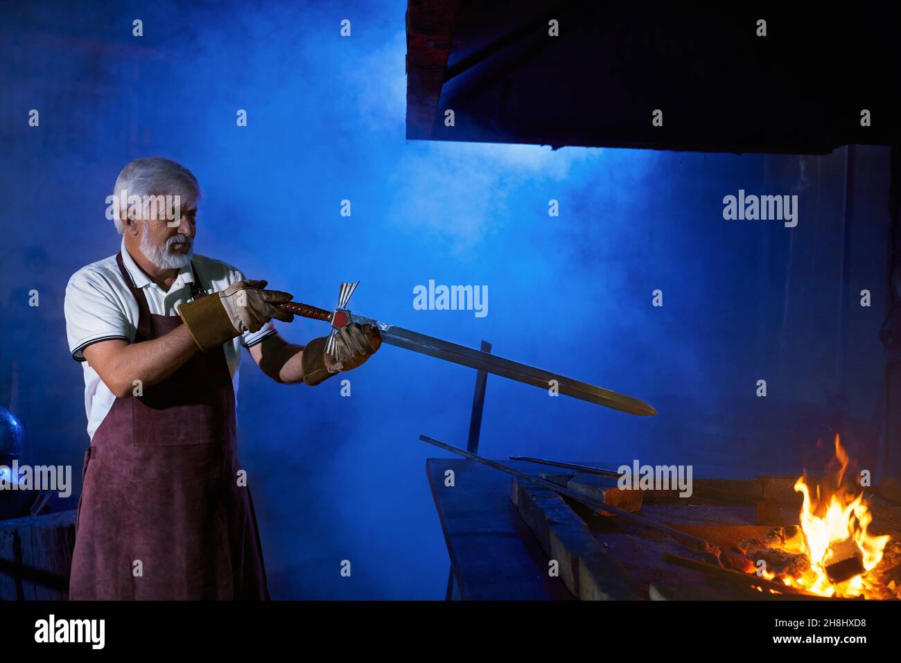 Caucasian grey haired man holding sharp sword in hands while standing ...