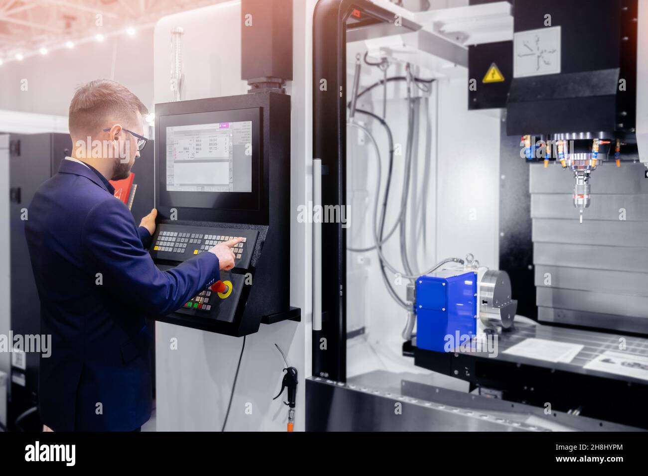 Worker man entering data in CNC machine at automatic factory floor ...