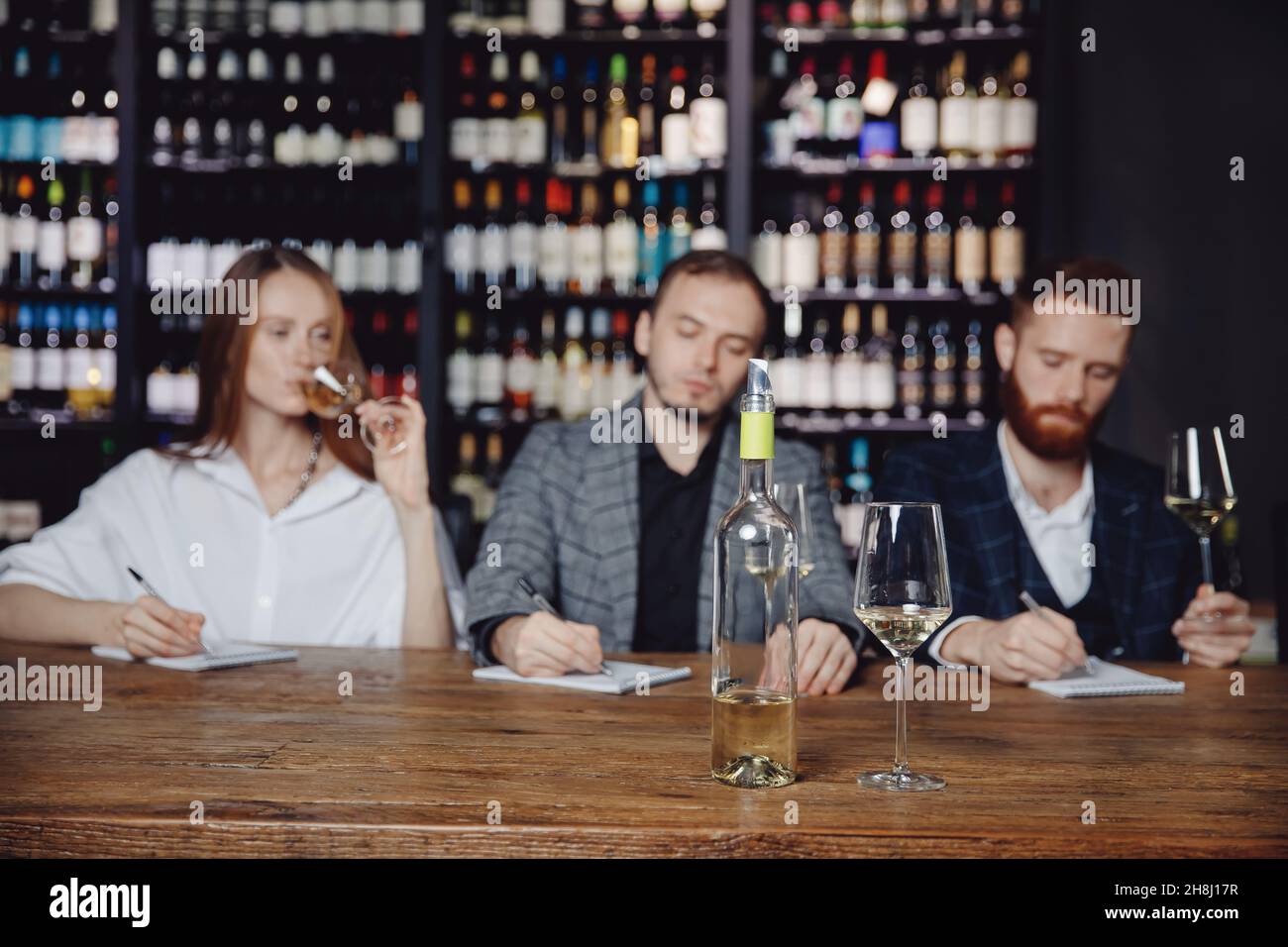 Sommeliers female and male tasting white wine and making notes at ...