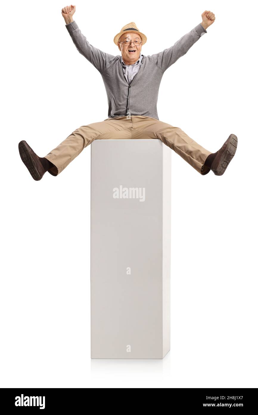 Happy elderly man sitting on a tall white column with hands up isolated ...