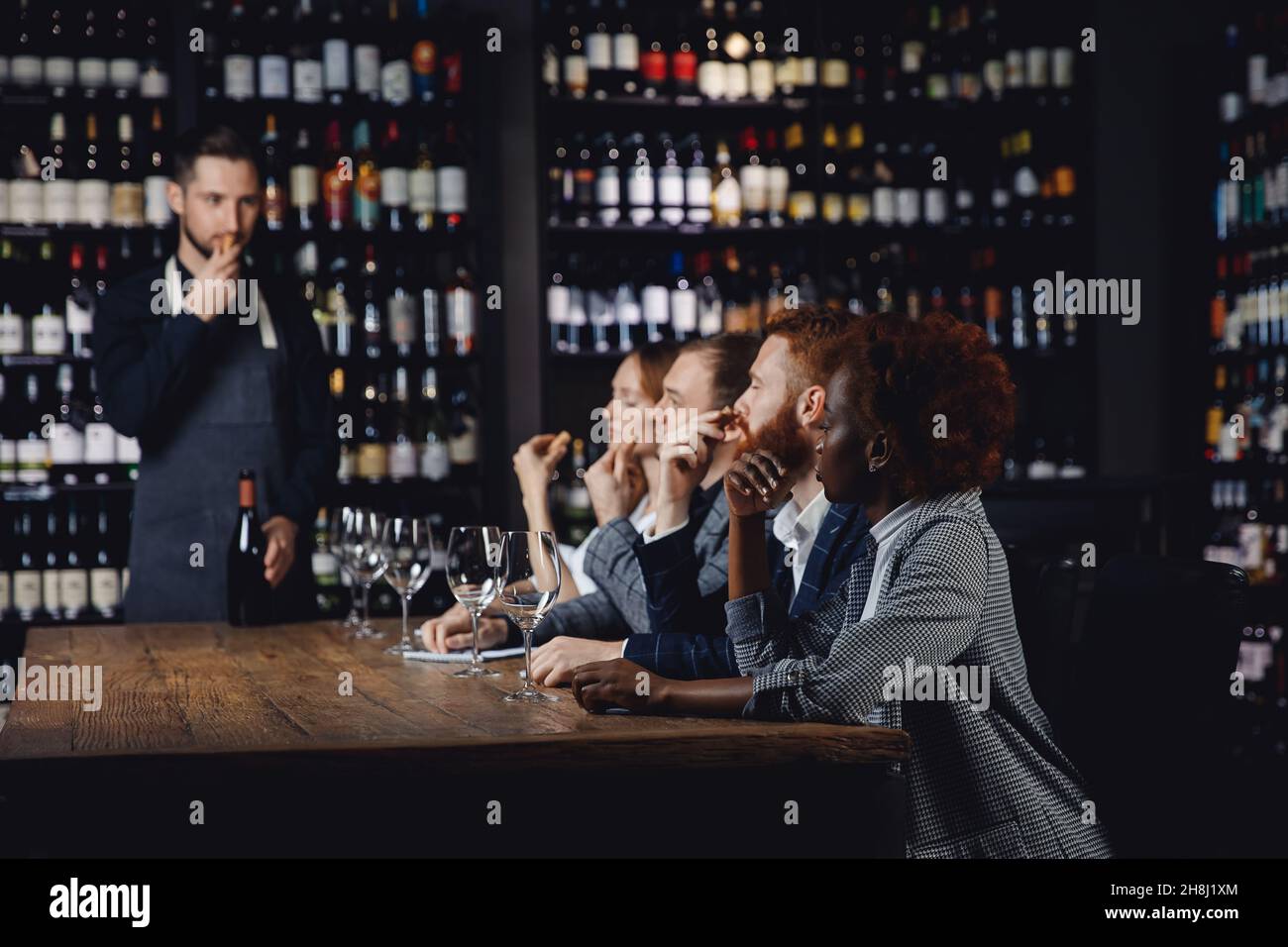 Sommelier training, European and African waiters sniffing red wine cork ...