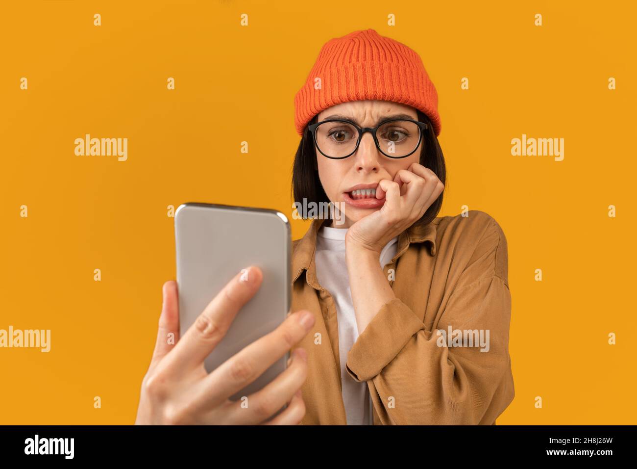 Portrait of scared young lady looking at smartphone in terror, seeing ...