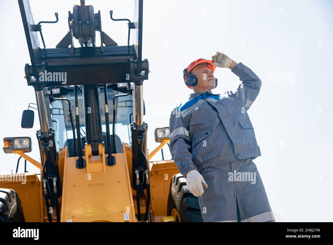 Man in helmet in front of bulldozer or excavator at construction site ...