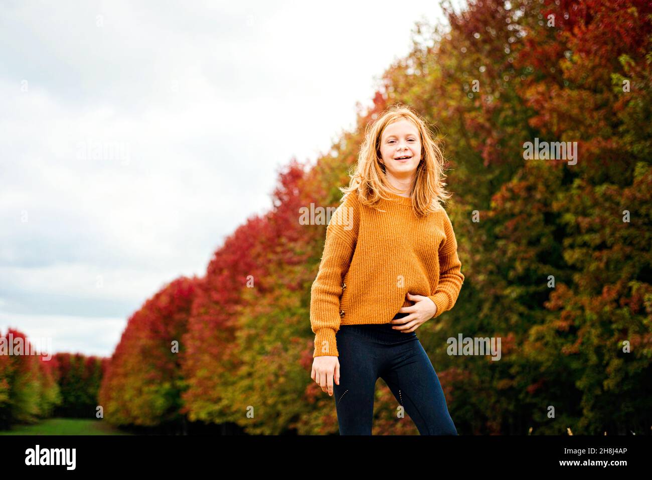 Happy tween girl surrounded by fall color trees Stock Photo - Alamy