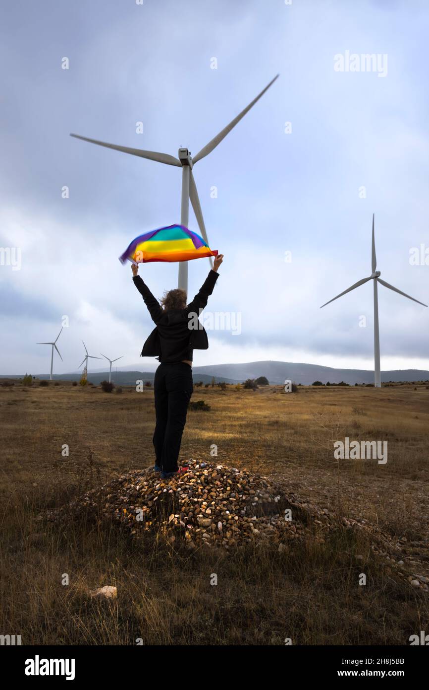 Woman standing on a small hill, her back unrecognizable raising a ...