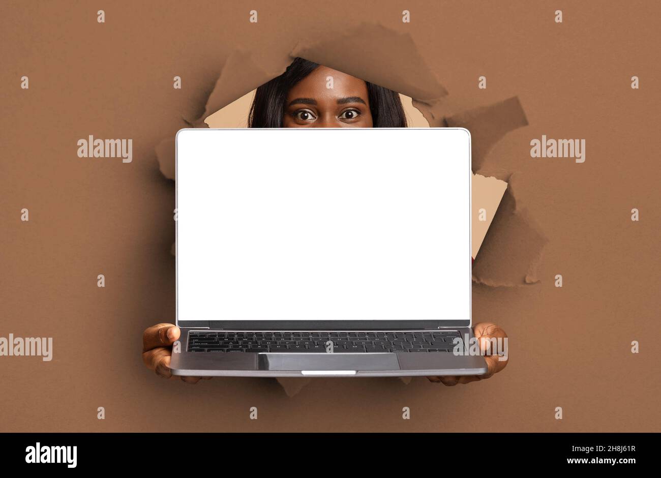 Black young lady showing empty laptop screen through torn paper Stock ...
