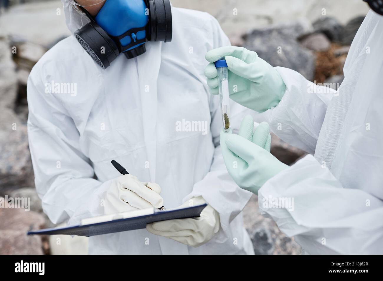 Close up of two scientists wearing hazmat suits collecting samples ...