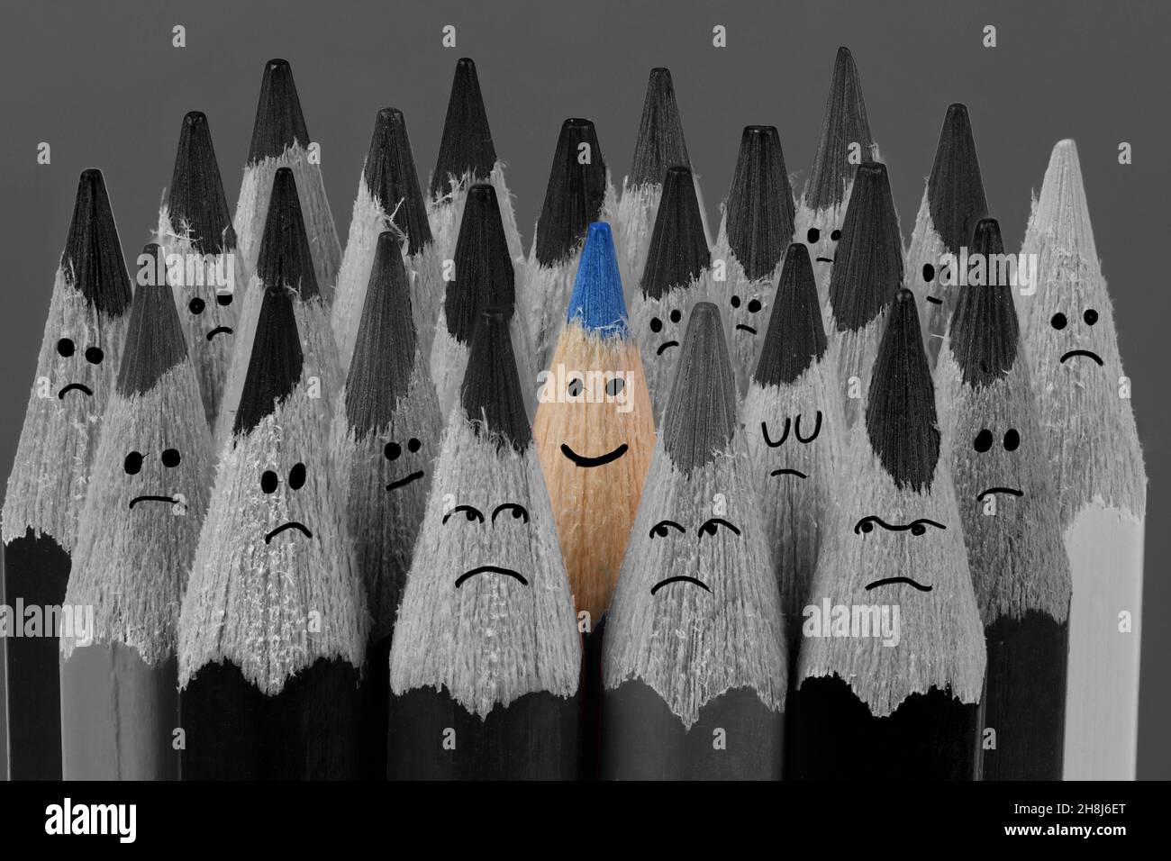 Bright colored smiling pencil among big set of black and white sad ...