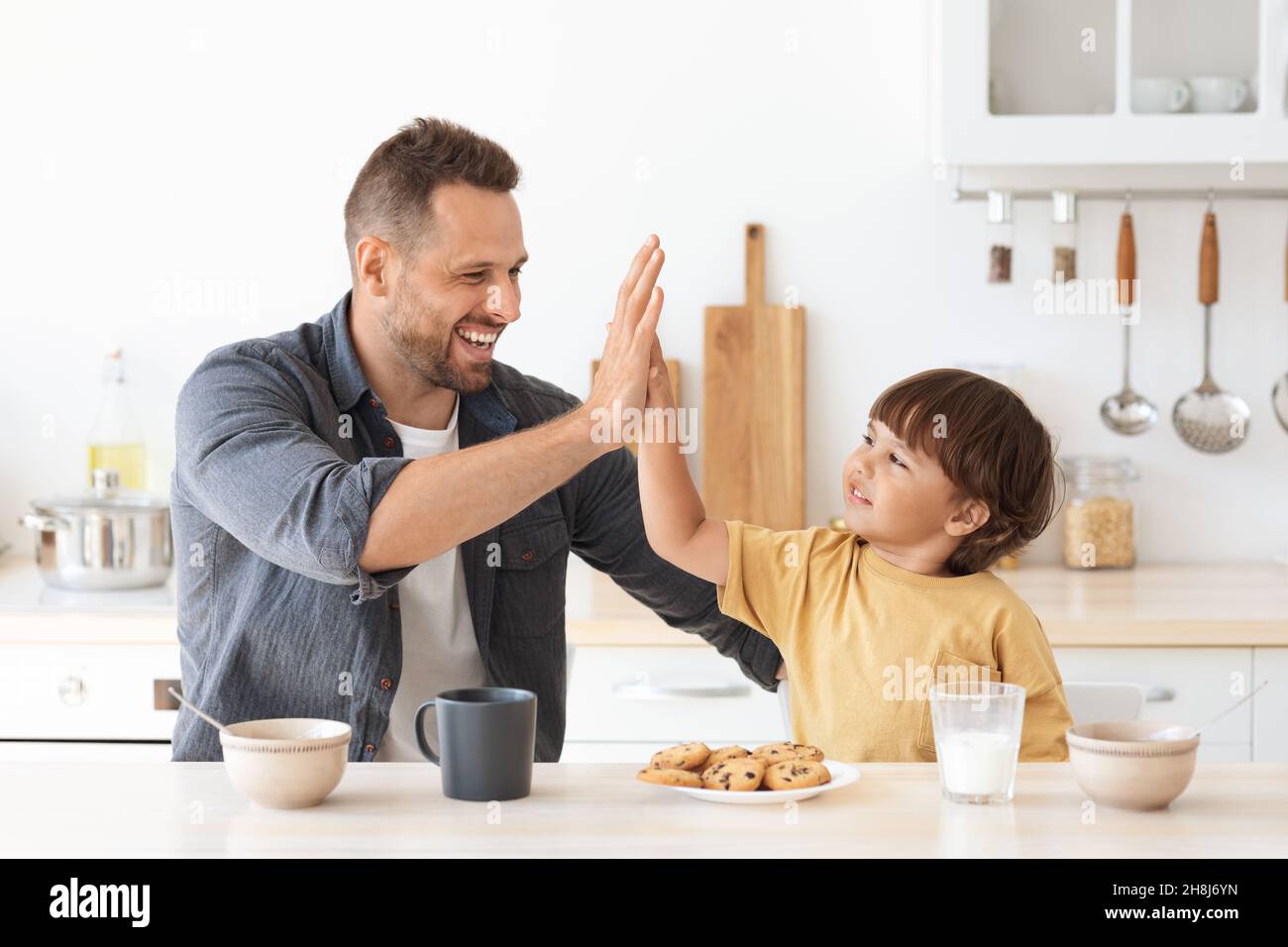 Positive father and little boy giving high five and smiling to each ...