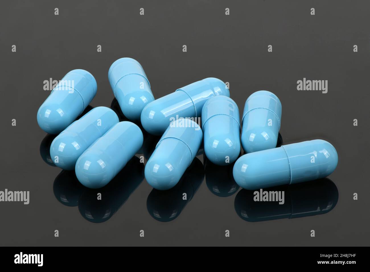 Blue medical capsules pill on acrylic black background. High resolution ...