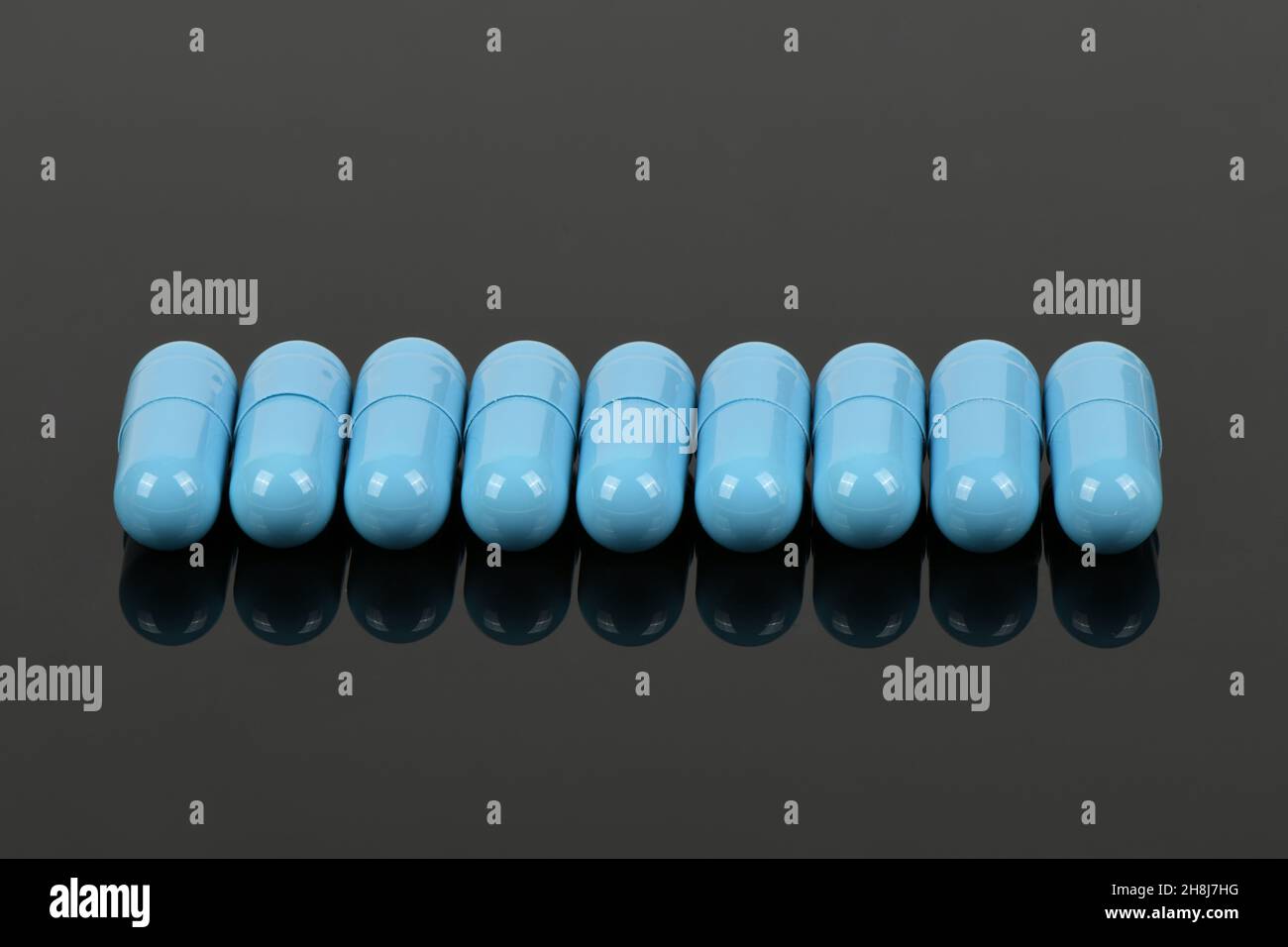 Blue medical capsules pill on acrylic black background. High resolution ...