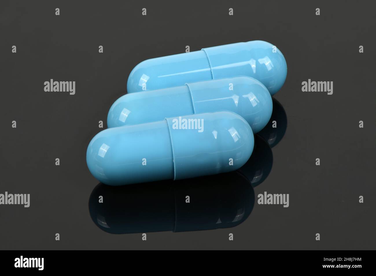 Blue medical capsules pill on acrylic black background. High resolution ...