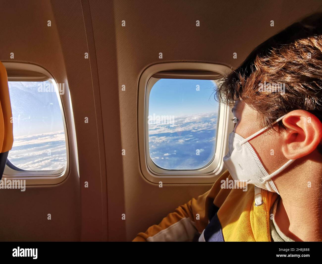 Male with a protective mask looking out the airplane window Stock Photo ...