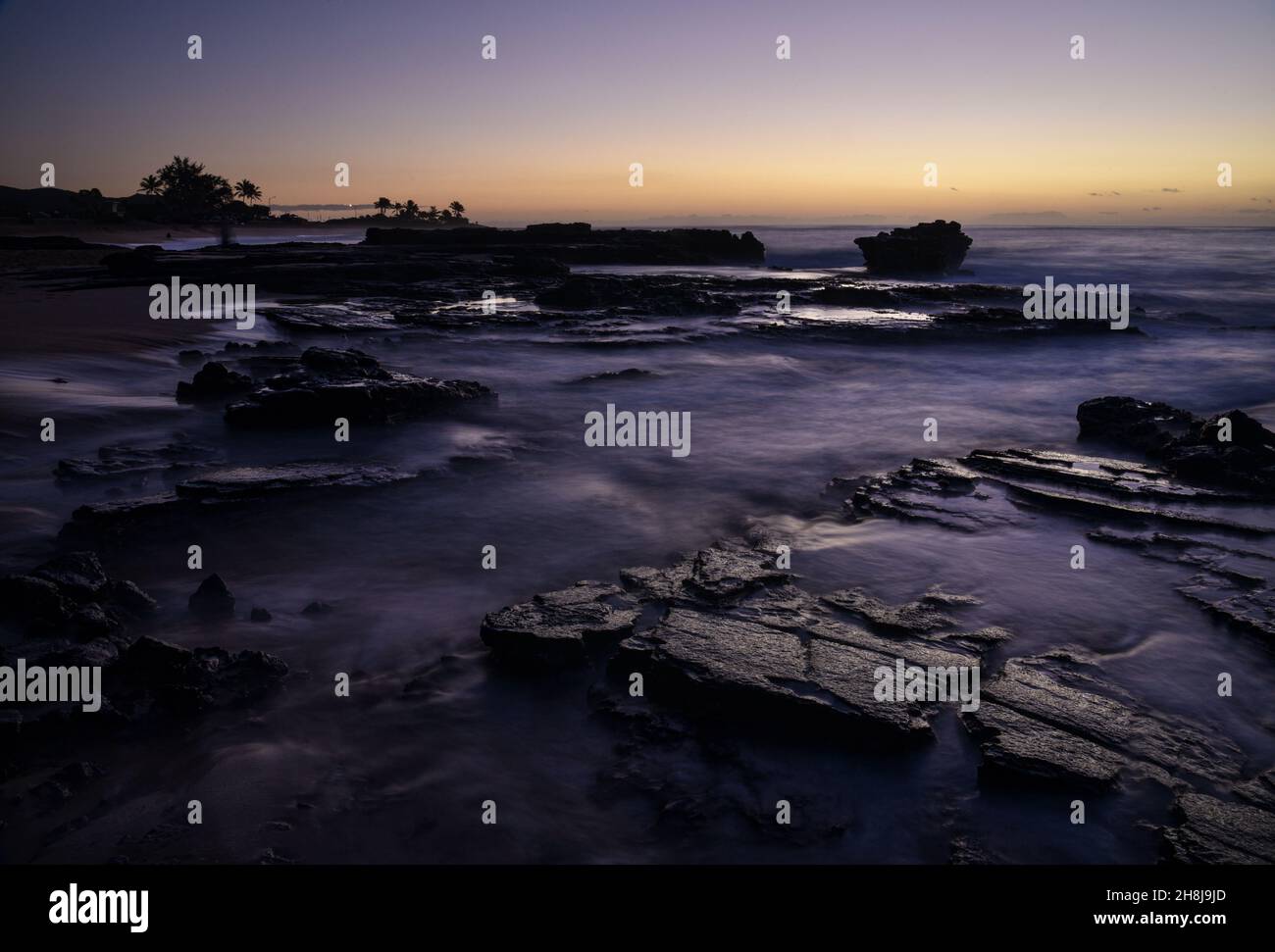Sunrise as the surf crashes on and swirls around volcanic lava rocks at ...
