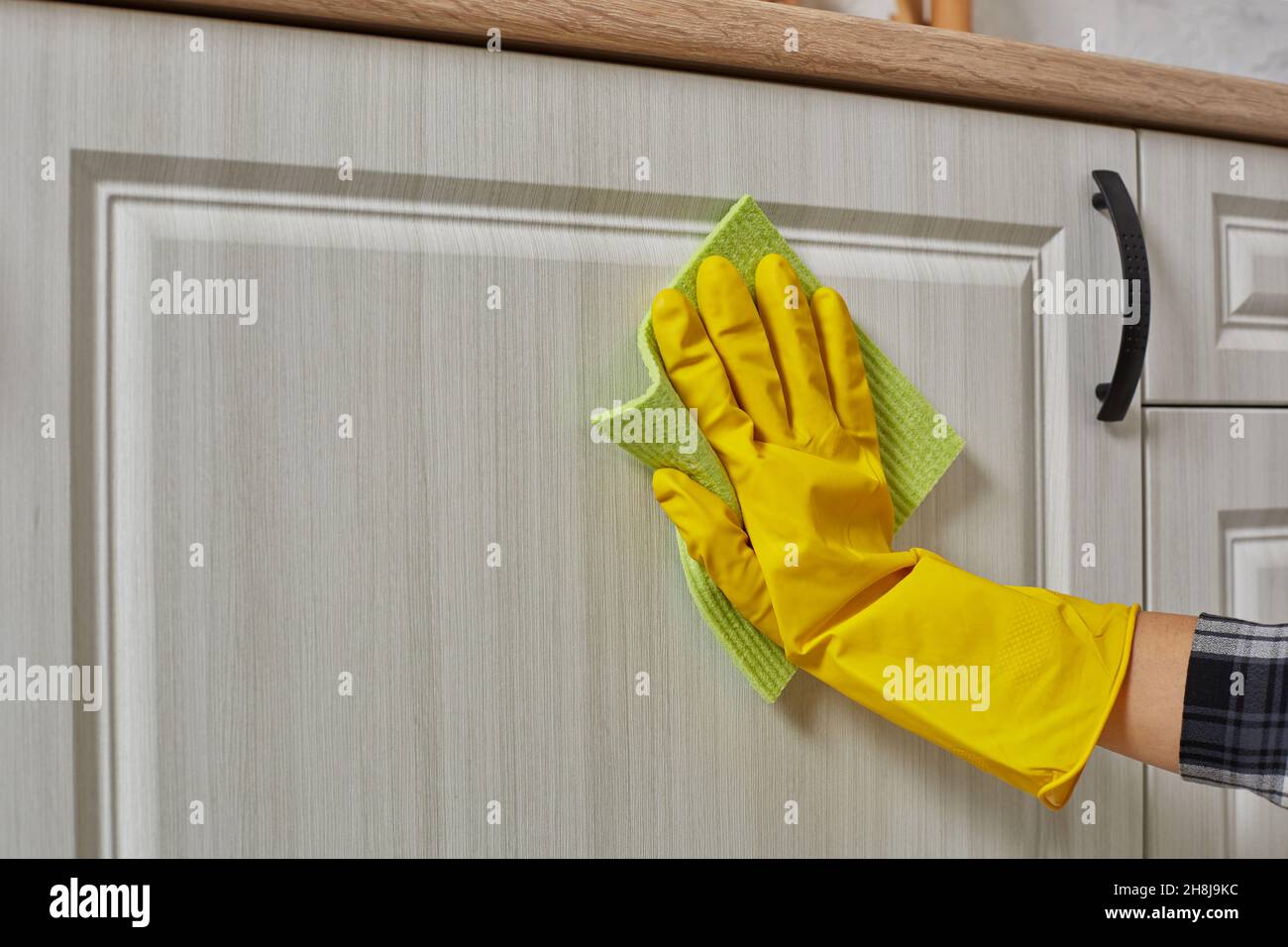 Hands in gloves with green rag is cleaning kitchen cabinets - housework ...