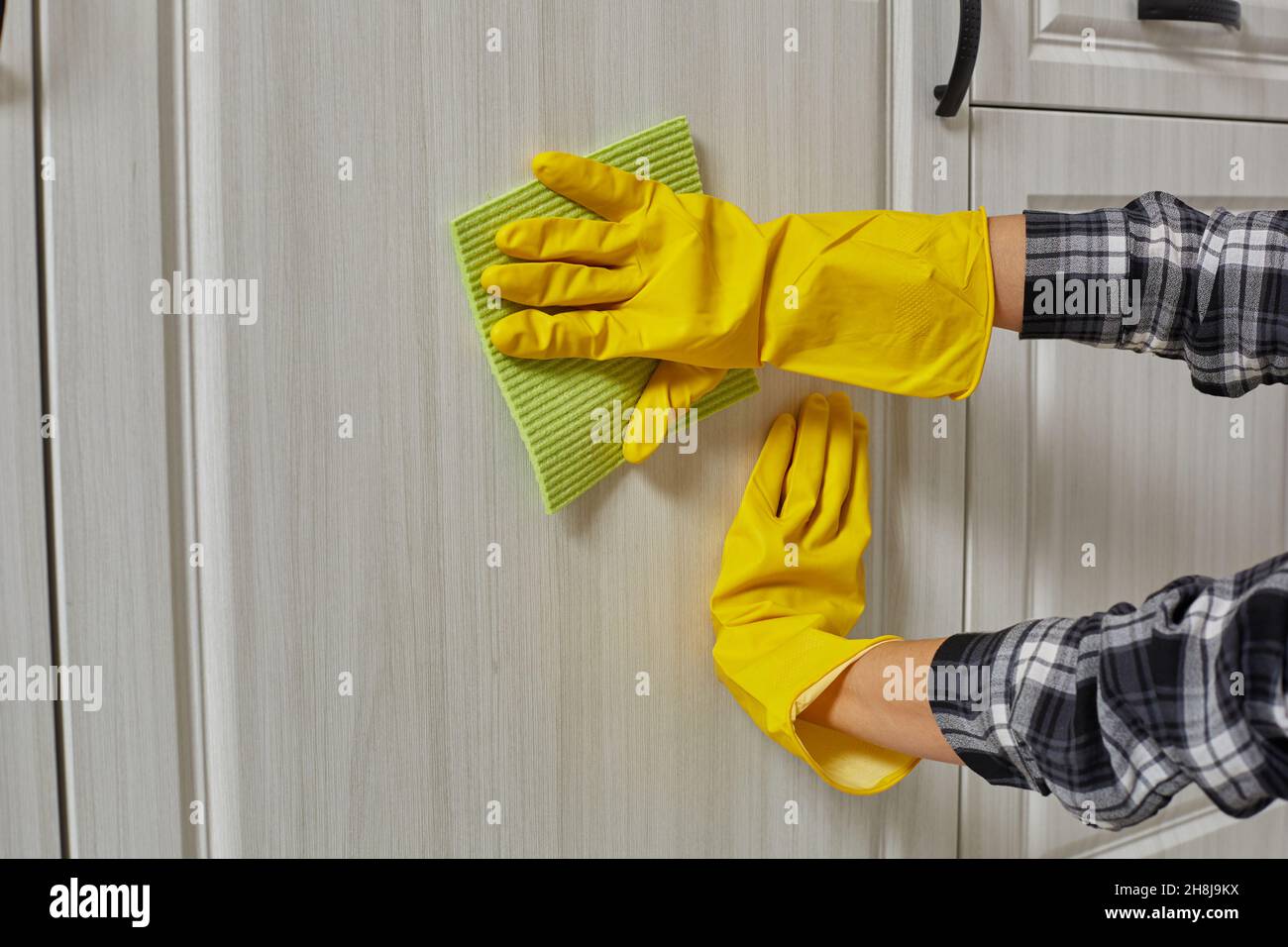 Hands in gloves with green rag is cleaning kitchen cabinets - housework ...