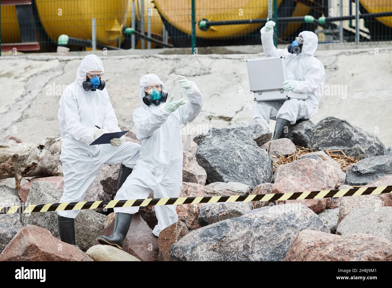 Group of people in hazmat suits working at ecological disaster site ...
