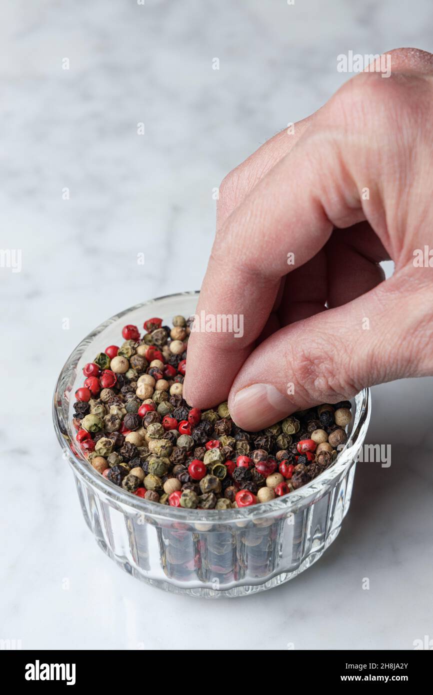 Hand grabbing pepper seeds from a bowl Stock Photo - Alamy